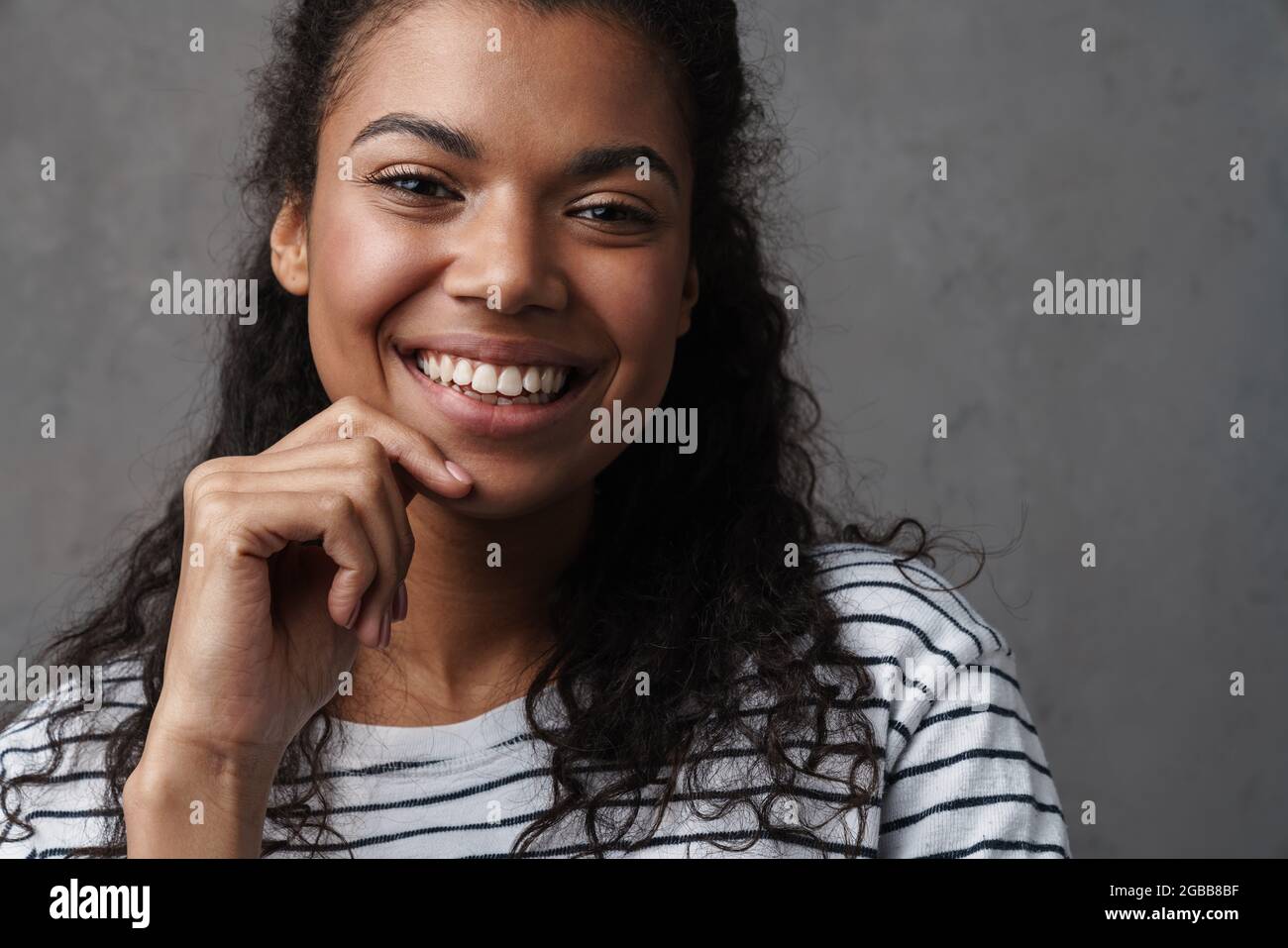 Happy smiling african casual brunette woman standing over gray wall ...