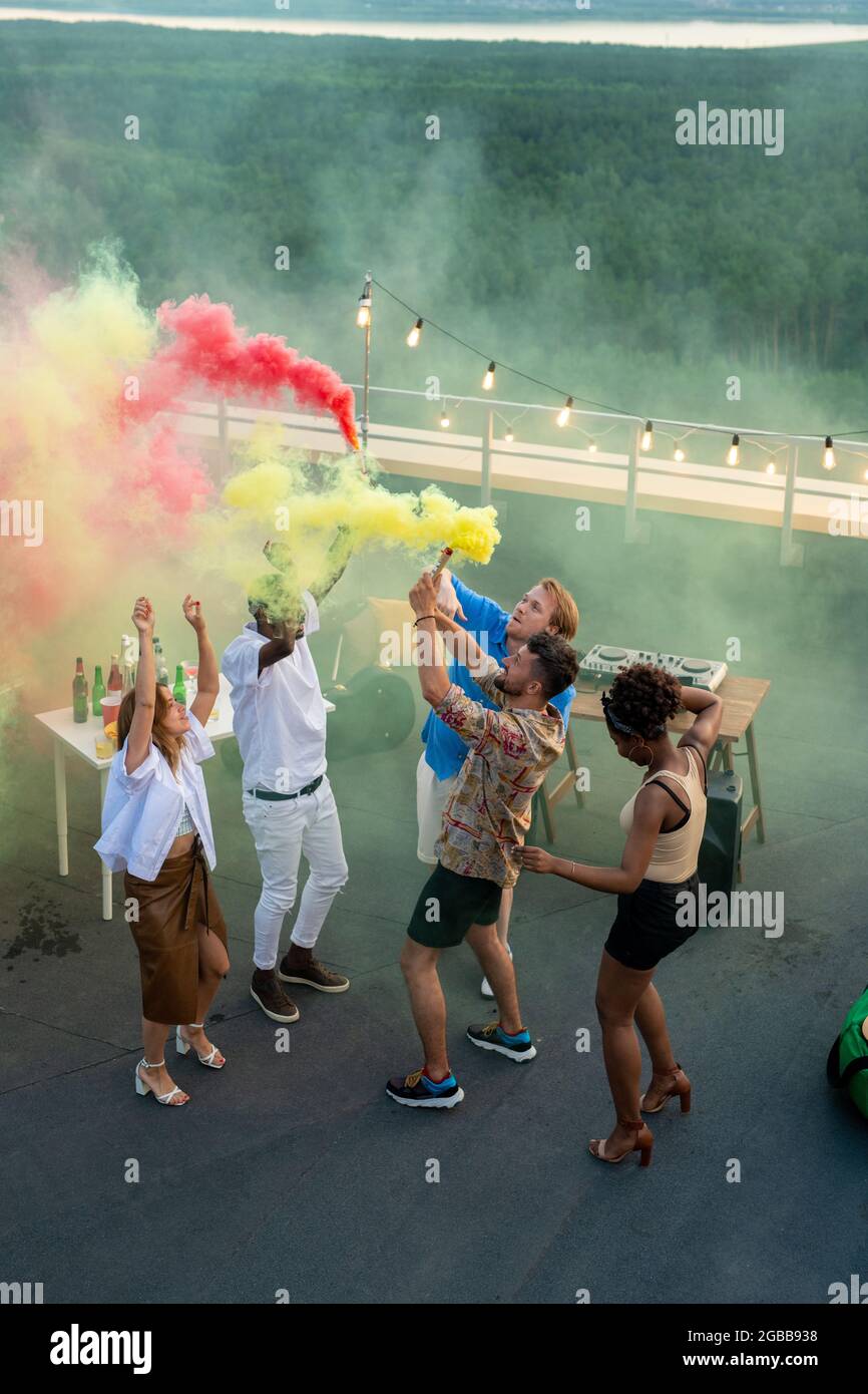 Intercultural young people with smoke crackers dancing together during ...
