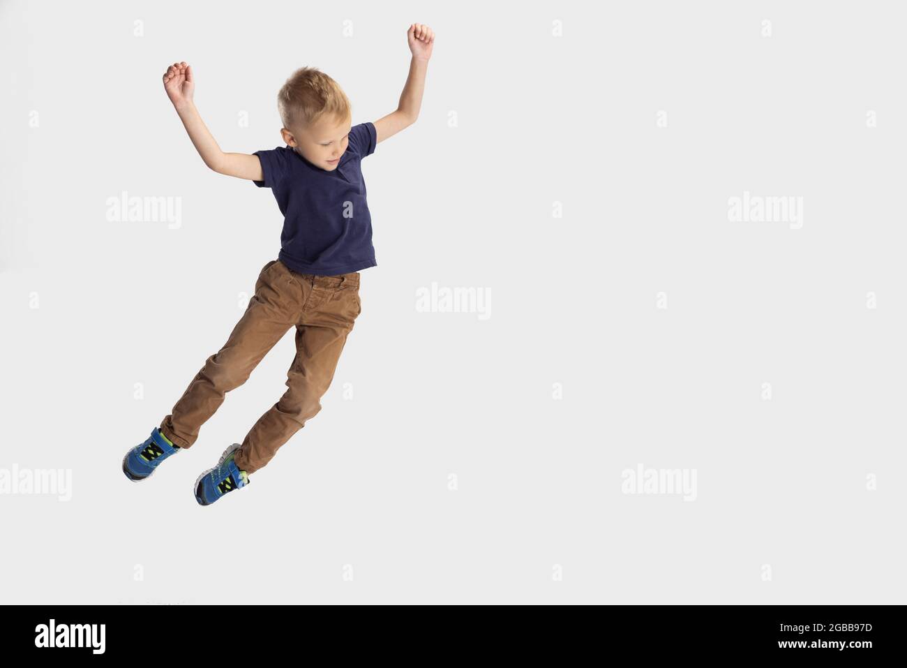Portrait of school boy, pupil falling down isolated on white studio ...
