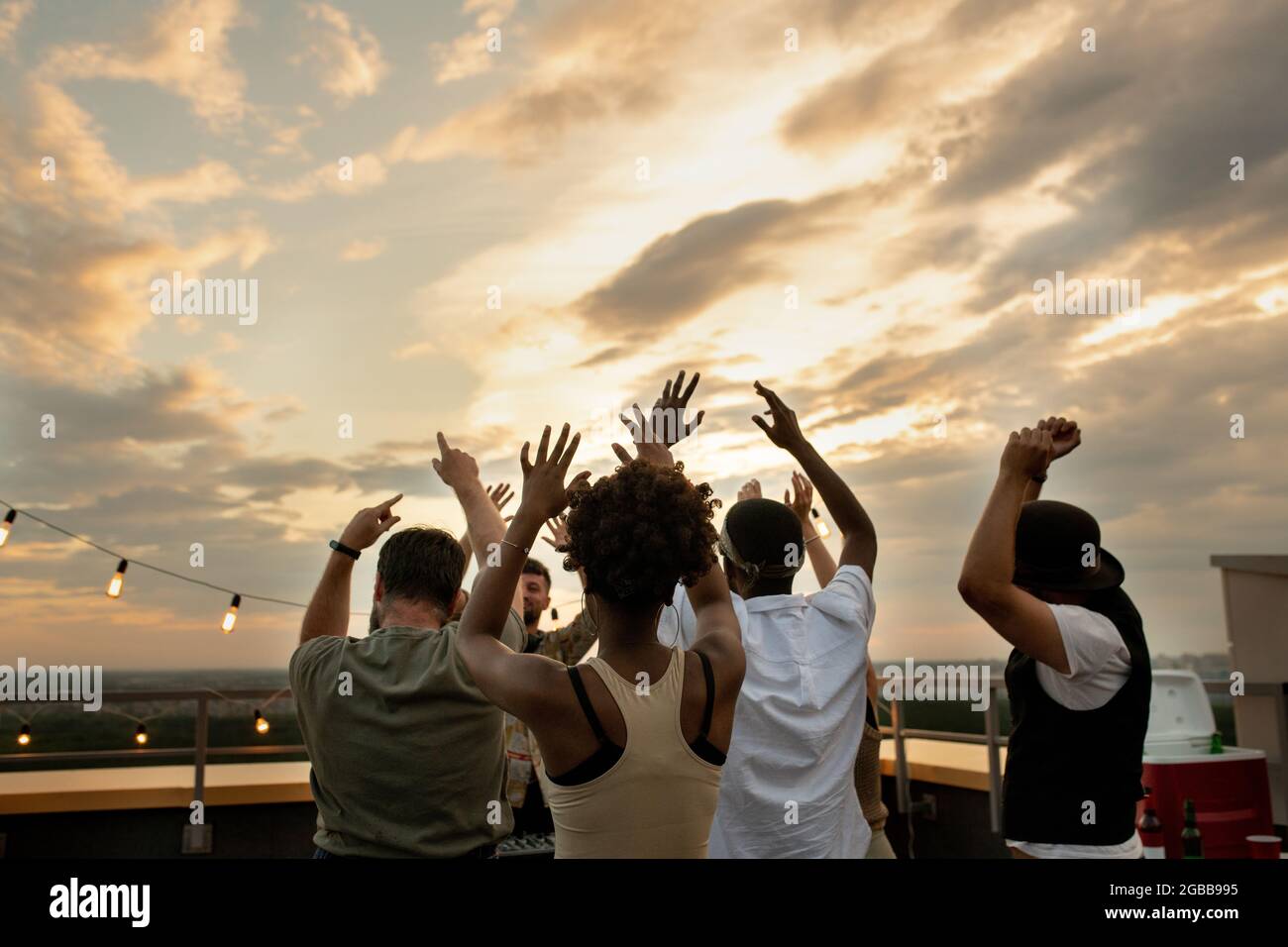 Rear view of young intercultural friends enjoying outdoor party on top ...