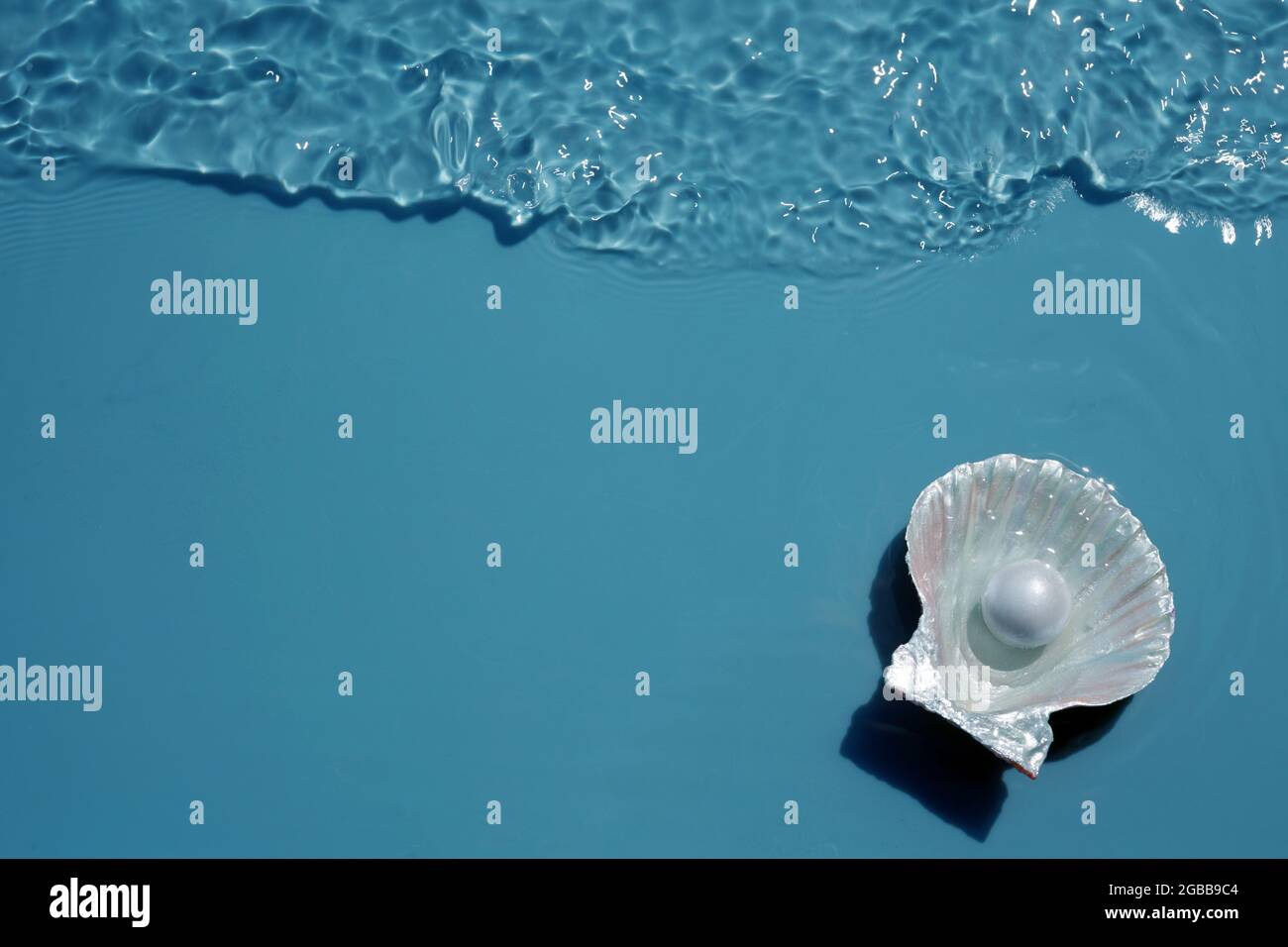 Shell with a pearl on blue water Stock Photo - Alamy