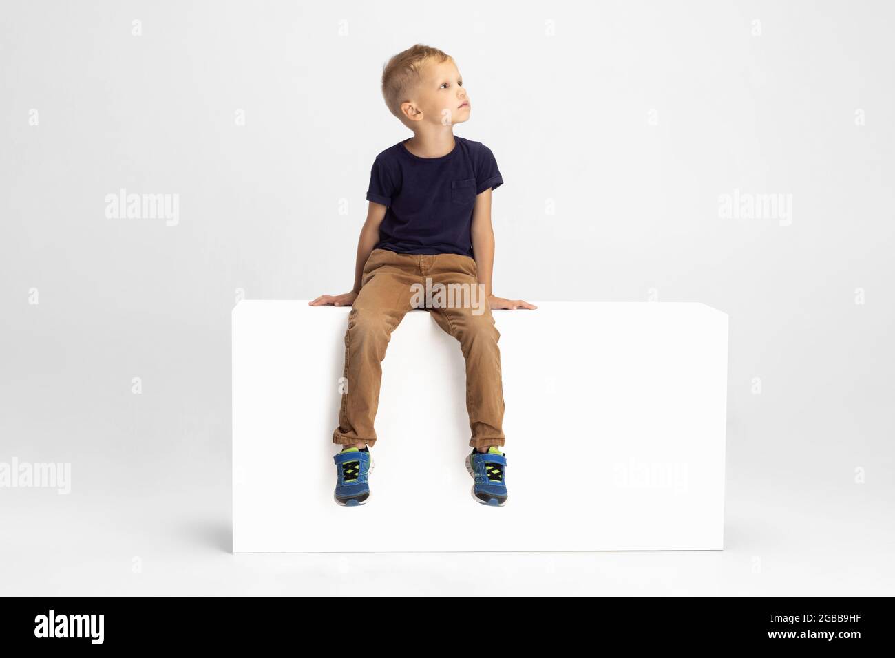 One preschool boy sitting on big box isolated on white studio ...
