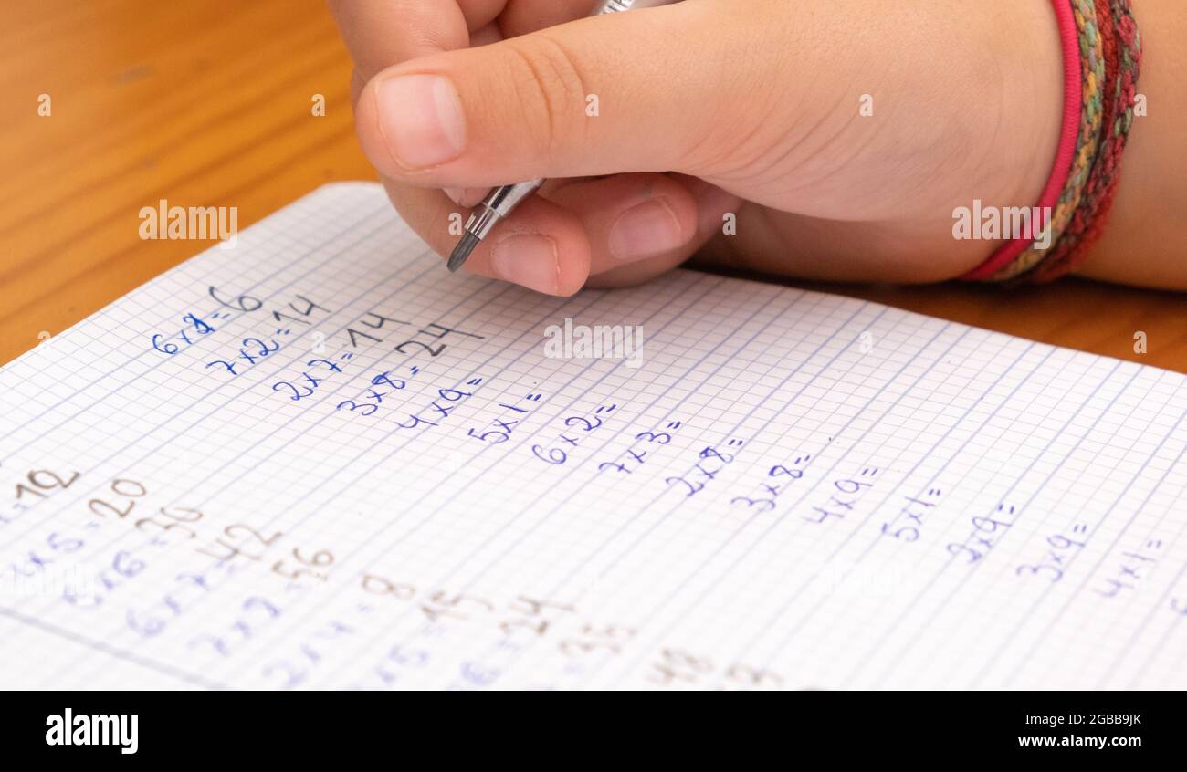 Side shot of a little girl's hand writing the multiplication tables ...