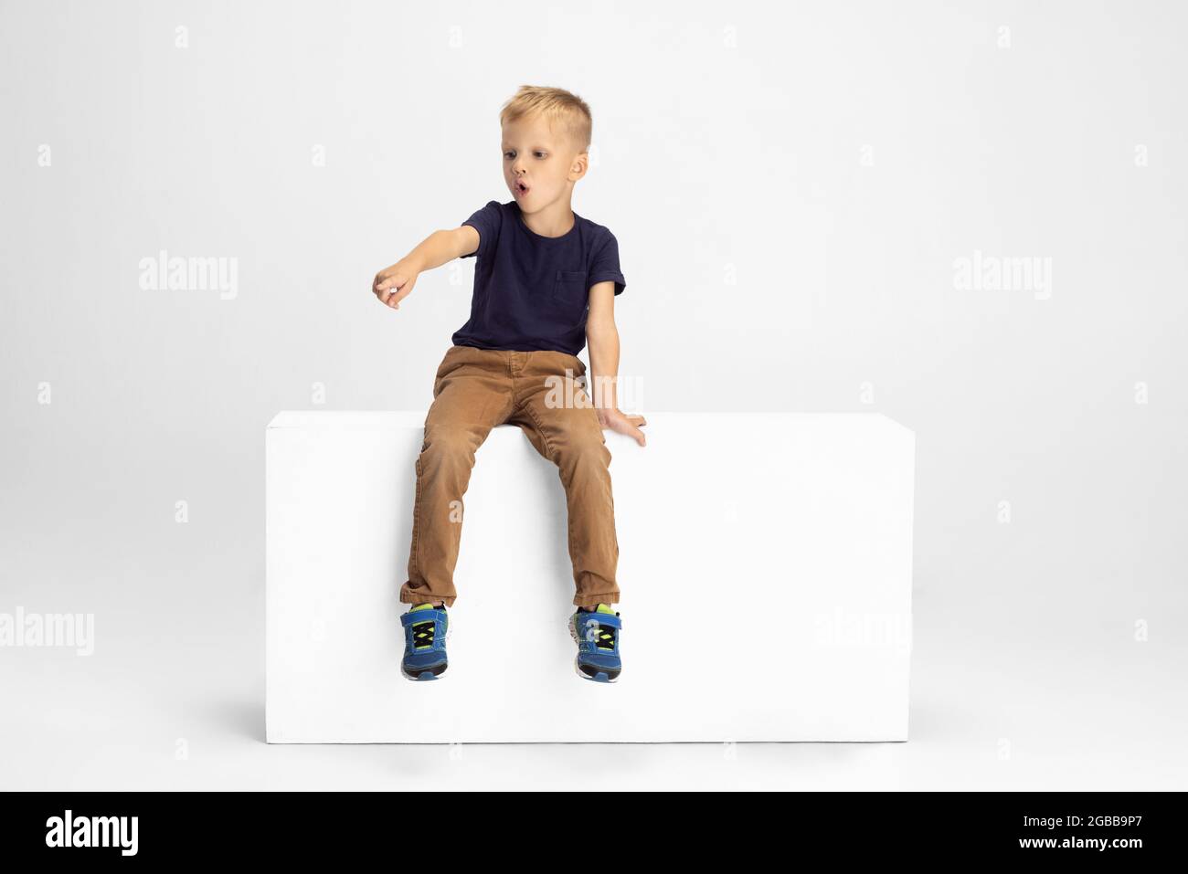 One preschool boy sitting on big box isolated on white studio ...
