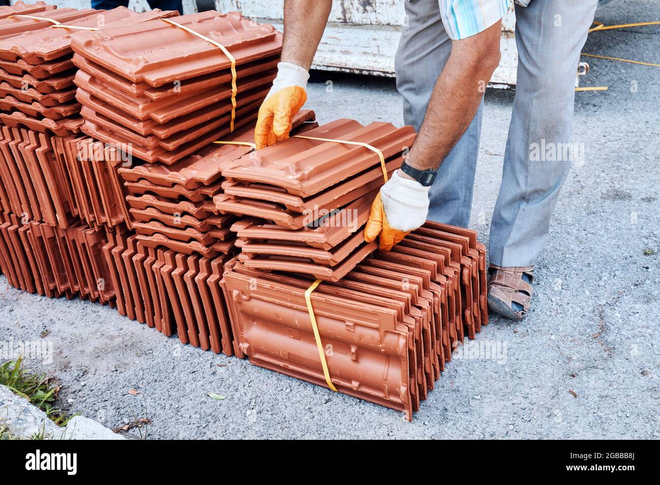 Construction worker arranging batch of roof tiles unloaded from a truck ...