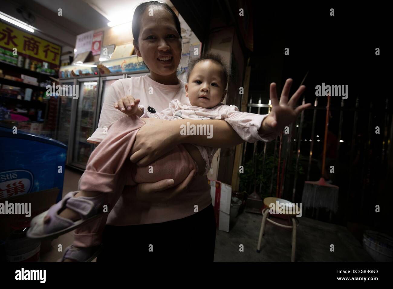 A Chinese mother and baby in their shop at night in Guangdong, China ...