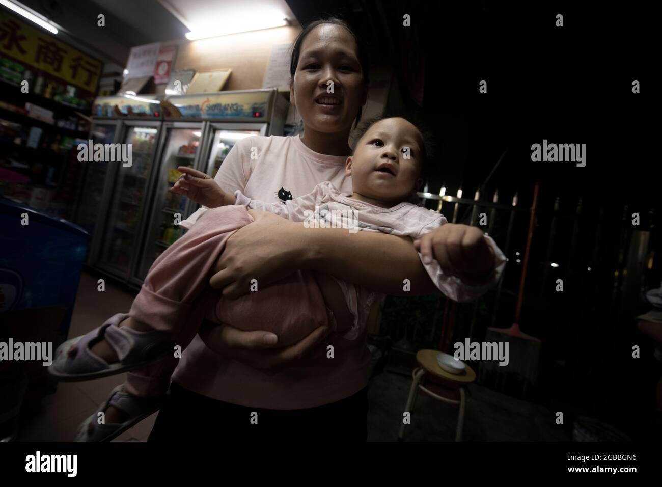 A Chinese mother and baby in their shop at night in Guangdong, China ...