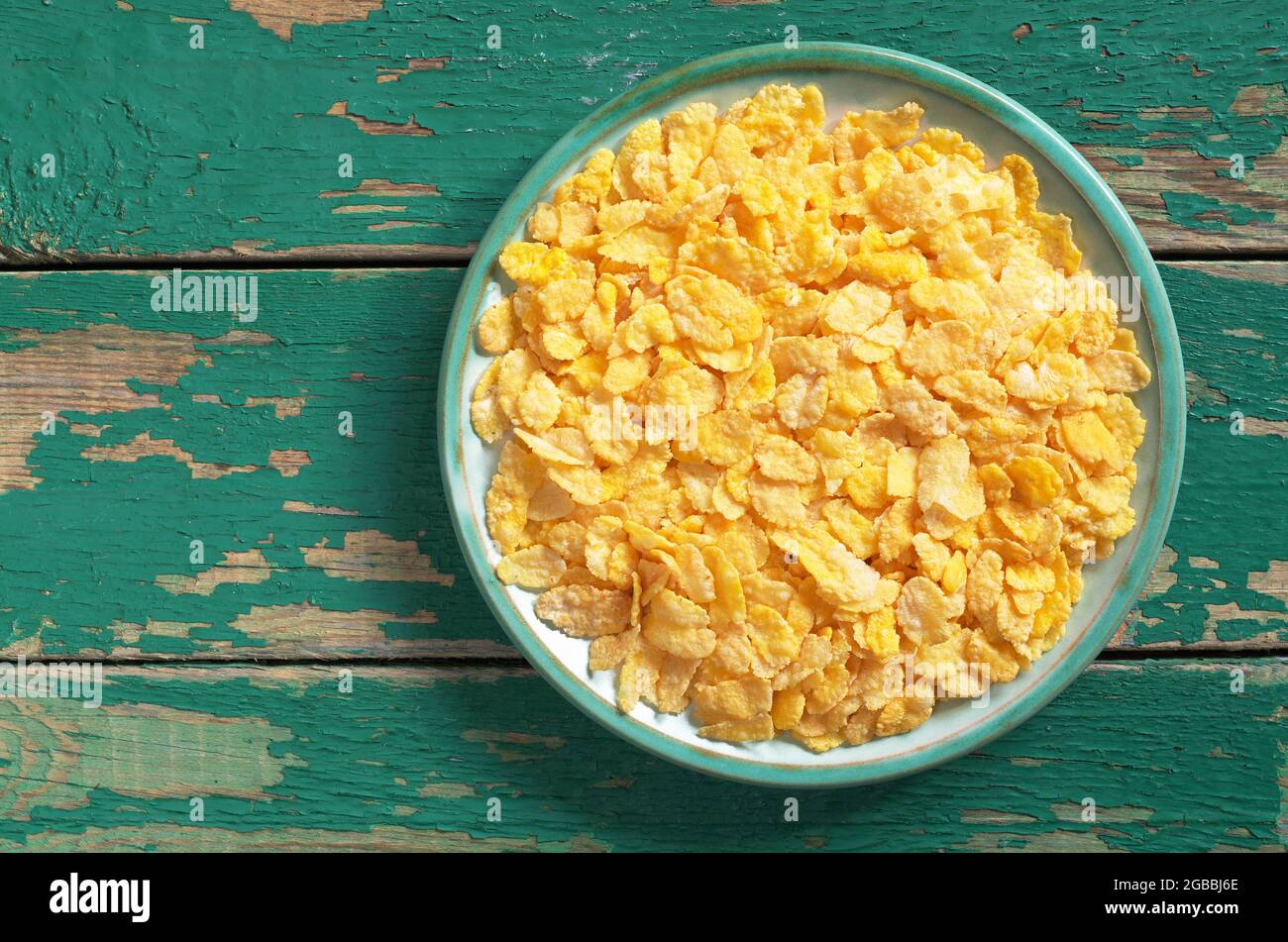 Cornflakes in plate on old green wooden table, top view Stock Photo - Alamy