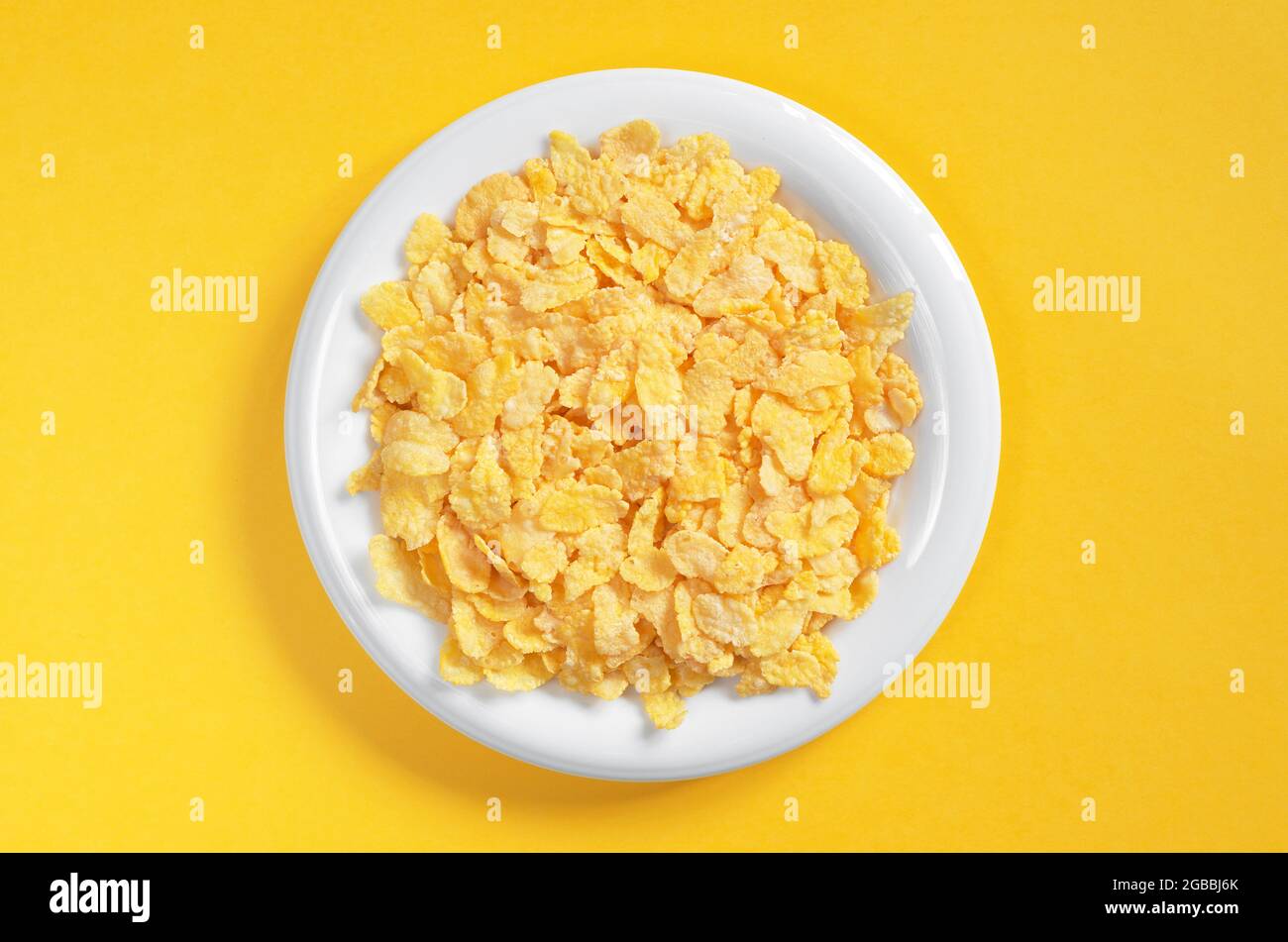 Cornflakes in white plate on yellow background, top view Stock Photo ...