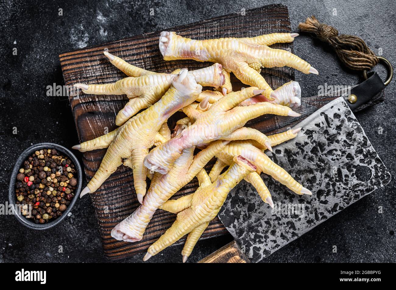 Raw Chicken feets on butcher cutting board with cleaver. Black ...