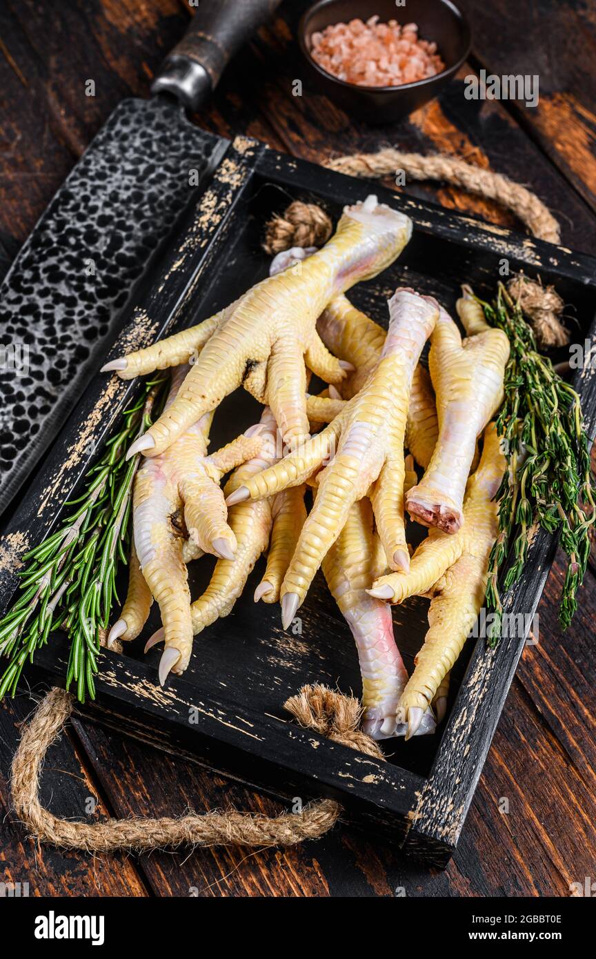 Raw Chicken paws feets on butcher chopping board with knife. Dark ...