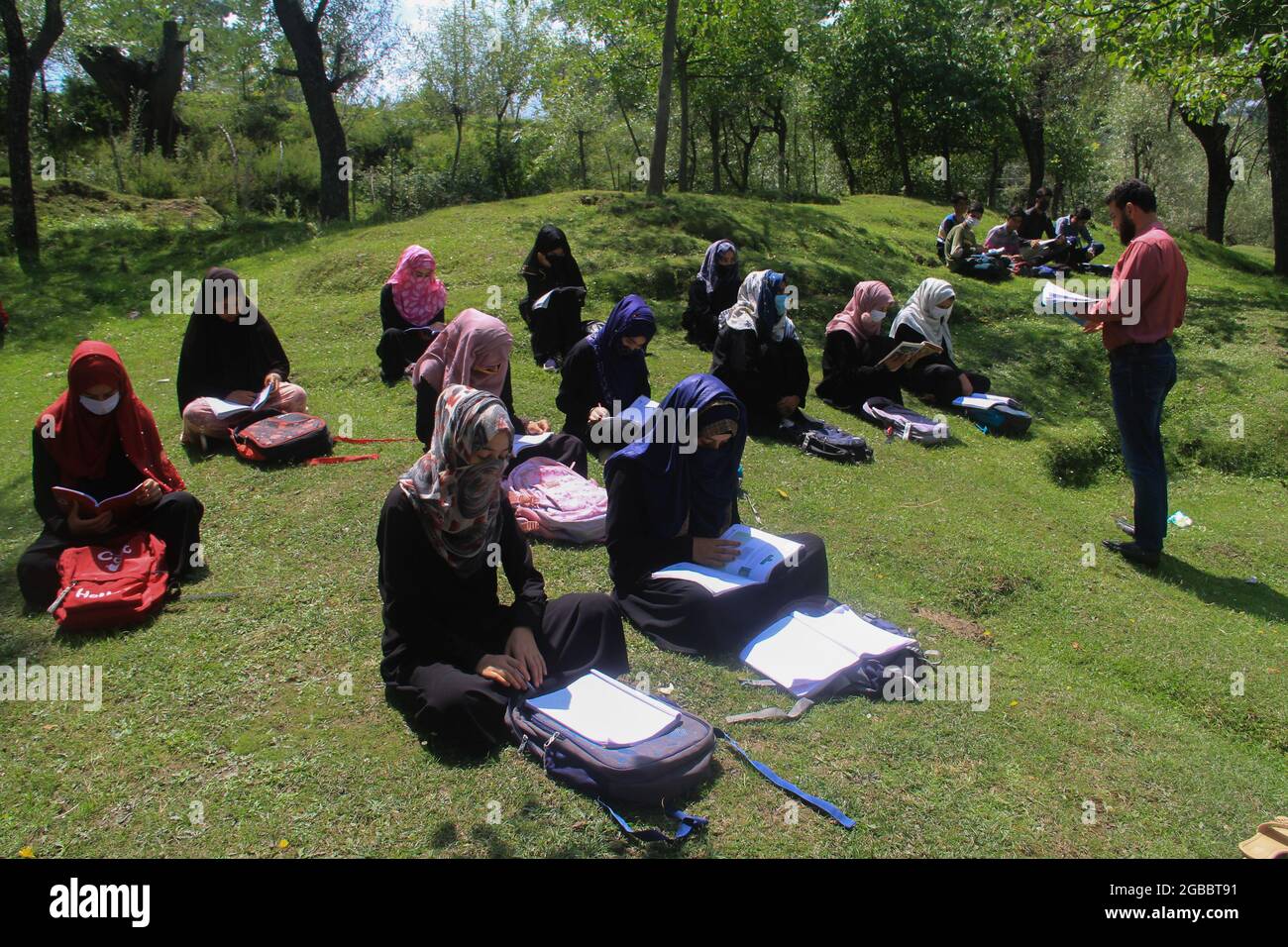 Kashmiri students attend a class at an open-air school on top of a ...