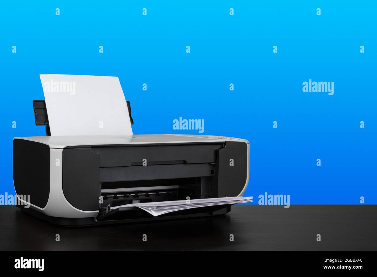 Compact laser printer on black desk against blue background Stock Photo ...