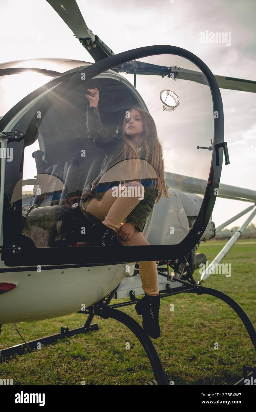 Preteen girl sitting in open cockpit of landed helicopter Stock Photo ...