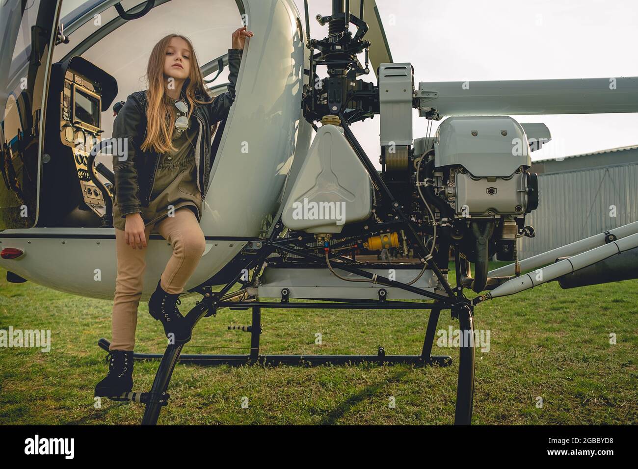 Tween girl posing near open cockpit of helicopter Stock Photo - Alamy