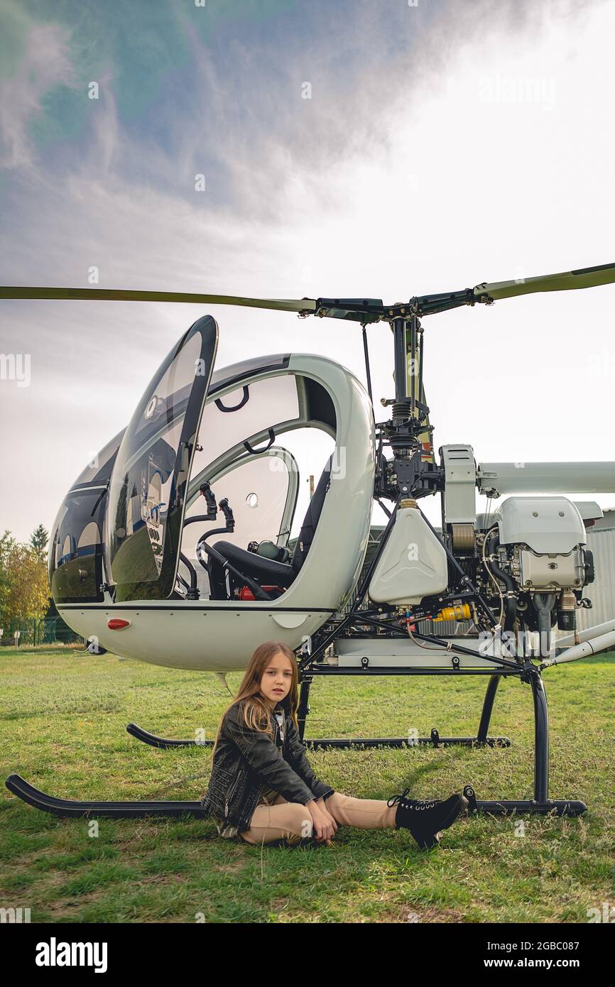 Tween girl sitting on green grass of flying field near helicopter Stock ...