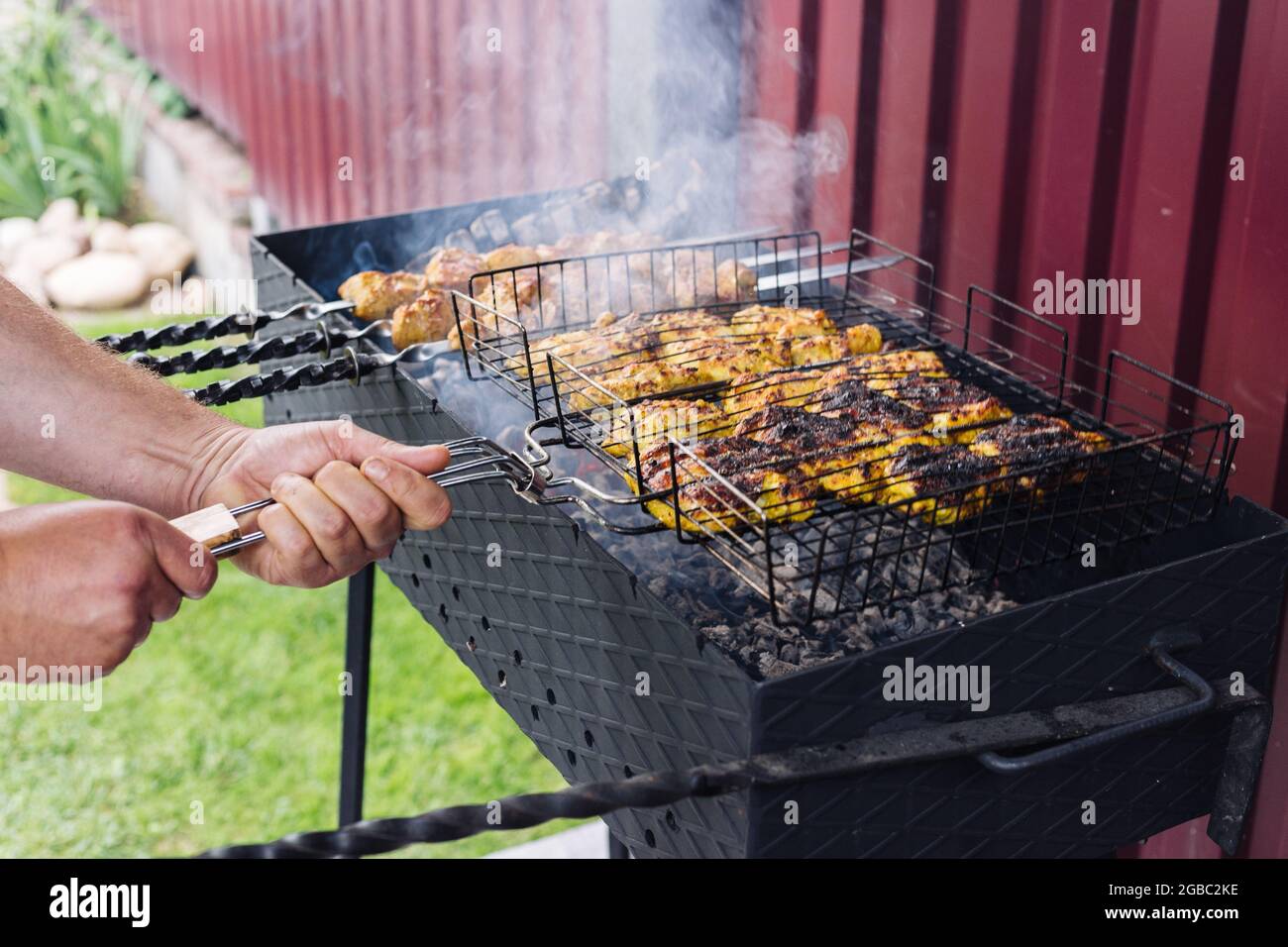 Hand rotates a skewer with a kebab on the grill Stock Photo - Alamy