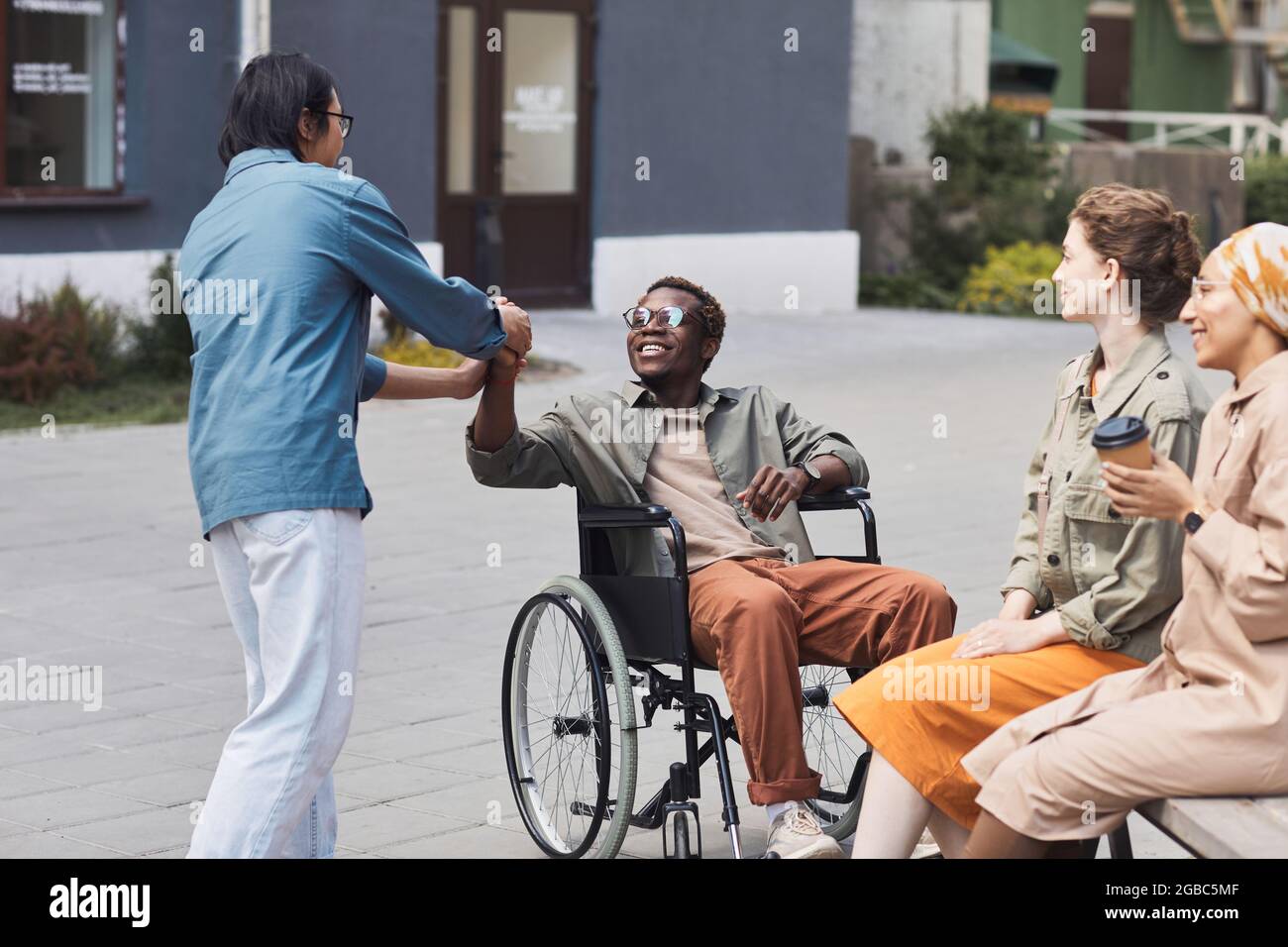 Group of young multi-ethnic friends including disabled man in ...