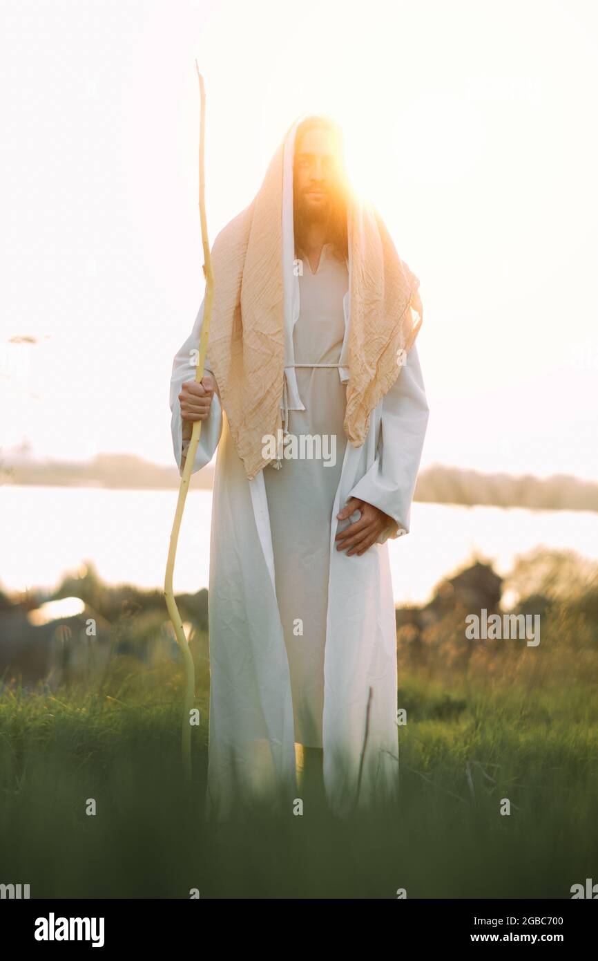 Jesus Christ with wooden staff stands in meadow clothed in his ...