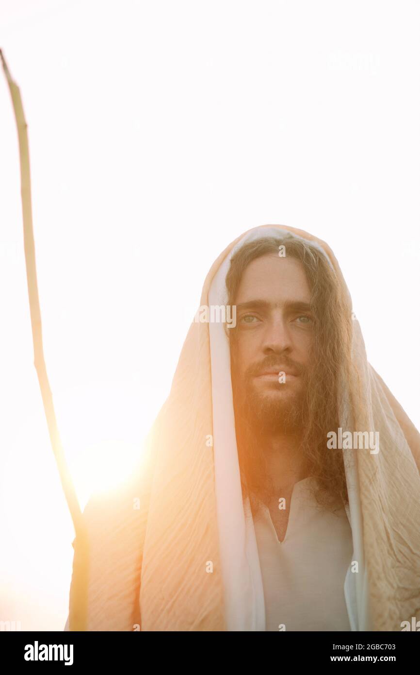 Jesus Christ with wooden staff stands in his traditional white robe ...