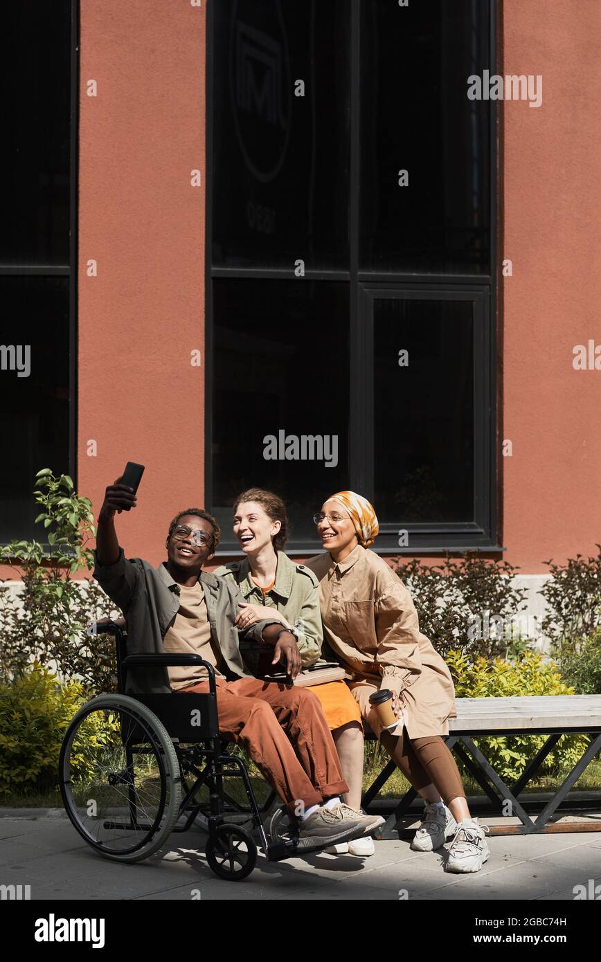 Positive young handicapped Black man in wheelchair using smartphone ...
