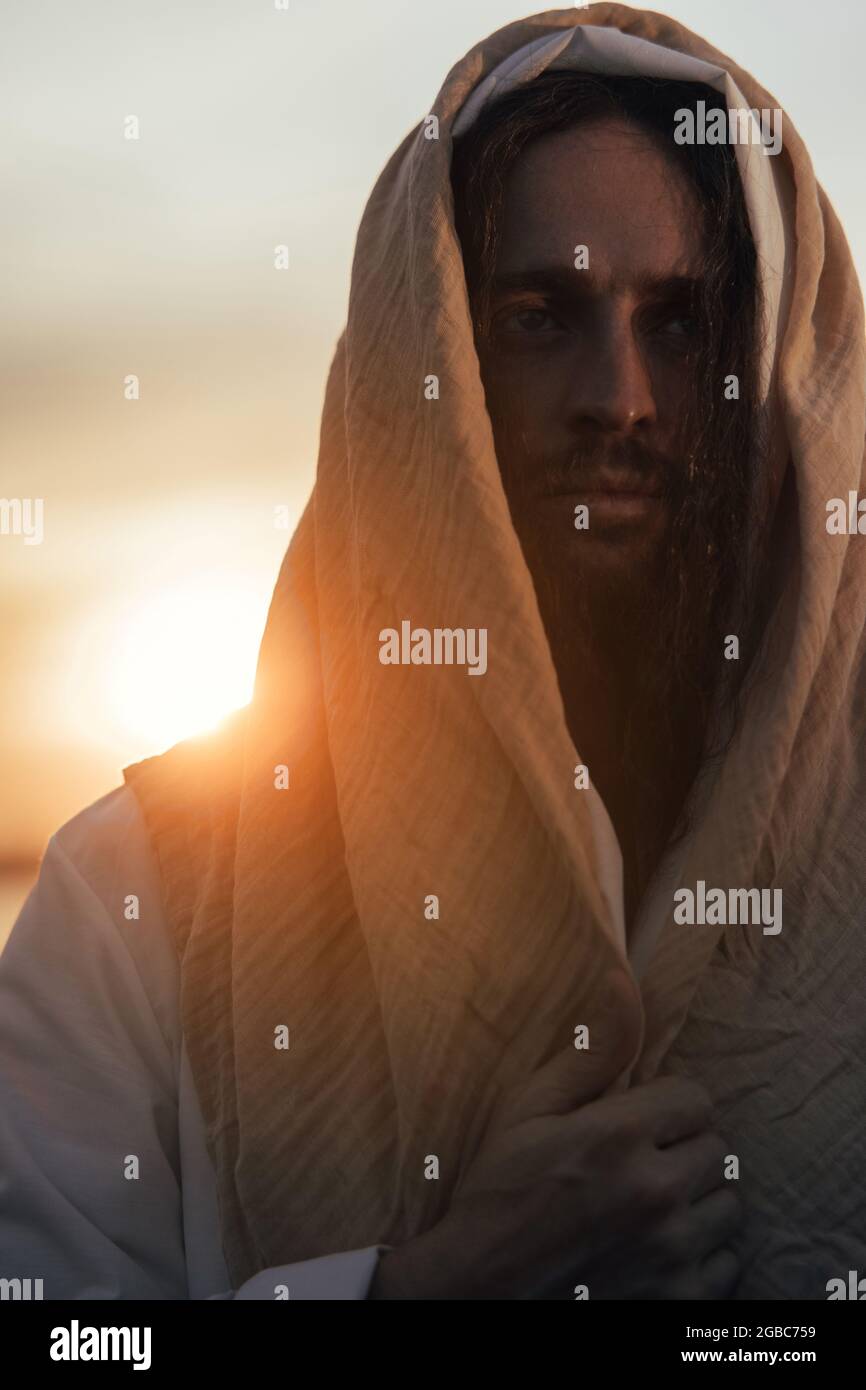 Portrait of Jesus Christ in his traditional white robe against sunset ...
