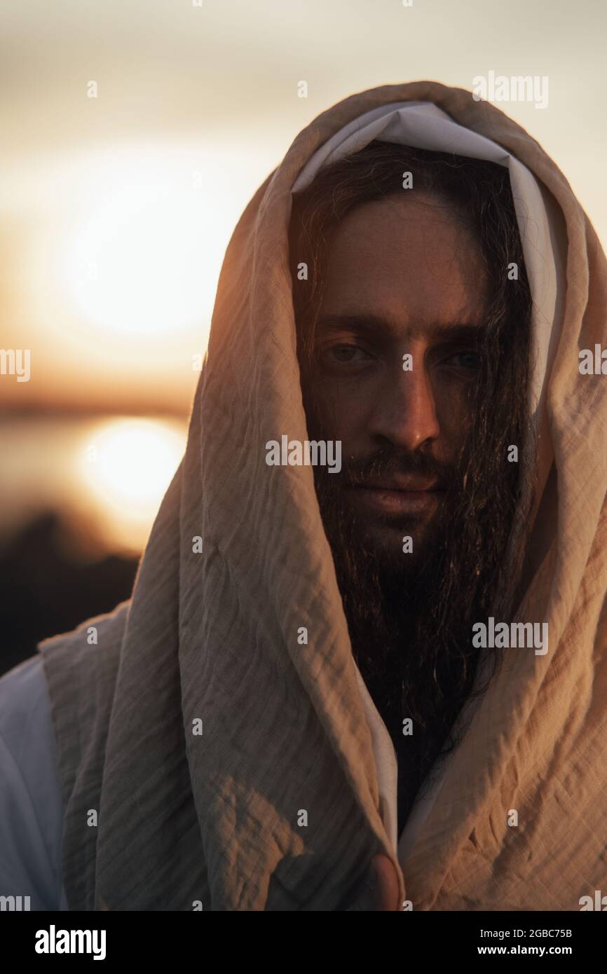 Portrait of Jesus Christ in his traditional white robe against sunset ...
