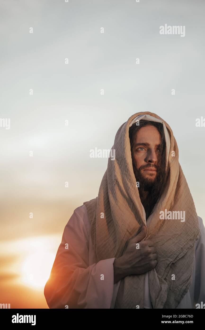 Portrait of Jesus Christ in his traditional white robe against sunset ...