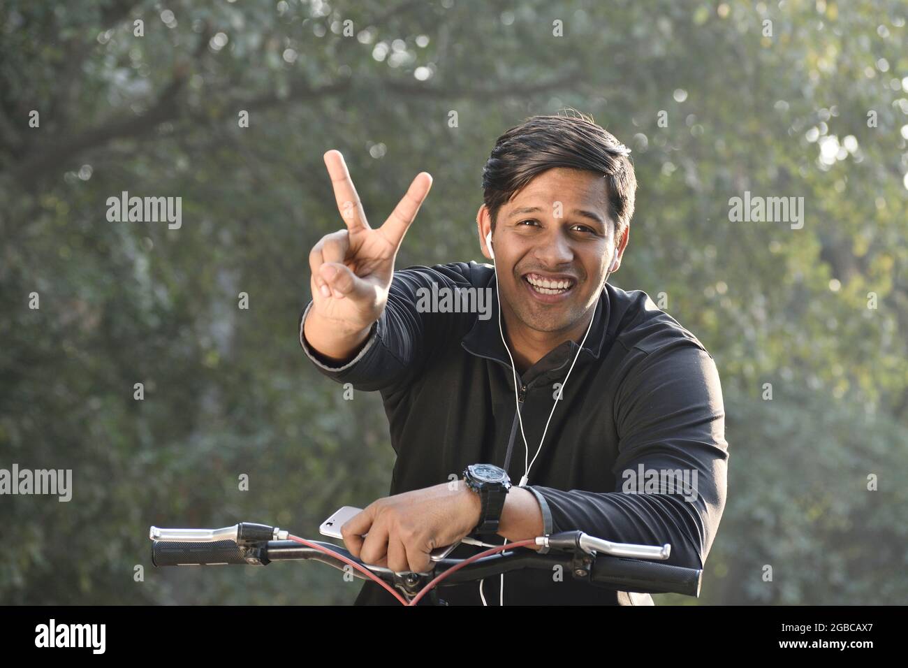 young Indian man on cycle showing victory sign form hand Stock Photo ...