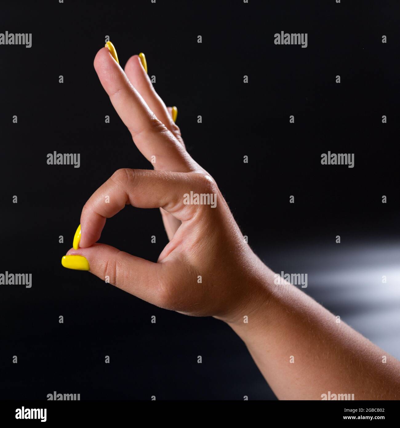 womans hand with manicure showing Ok sign, clode up on black background ...