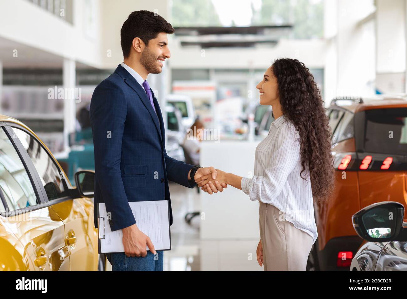 Sales assistant greeting pretty brunette lady, car salon interior Stock ...