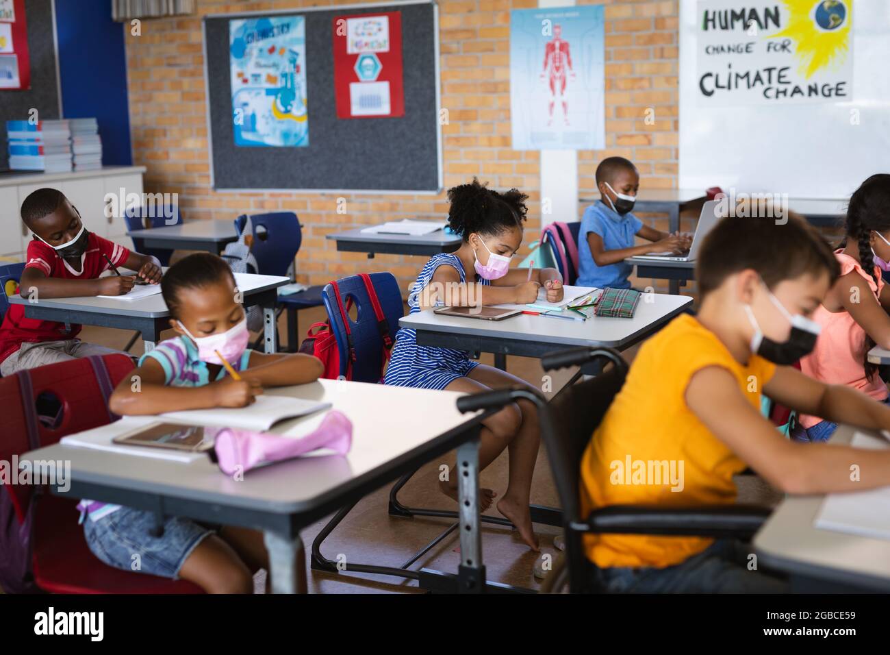 Group of students wearing face masks studying while sitting on their ...