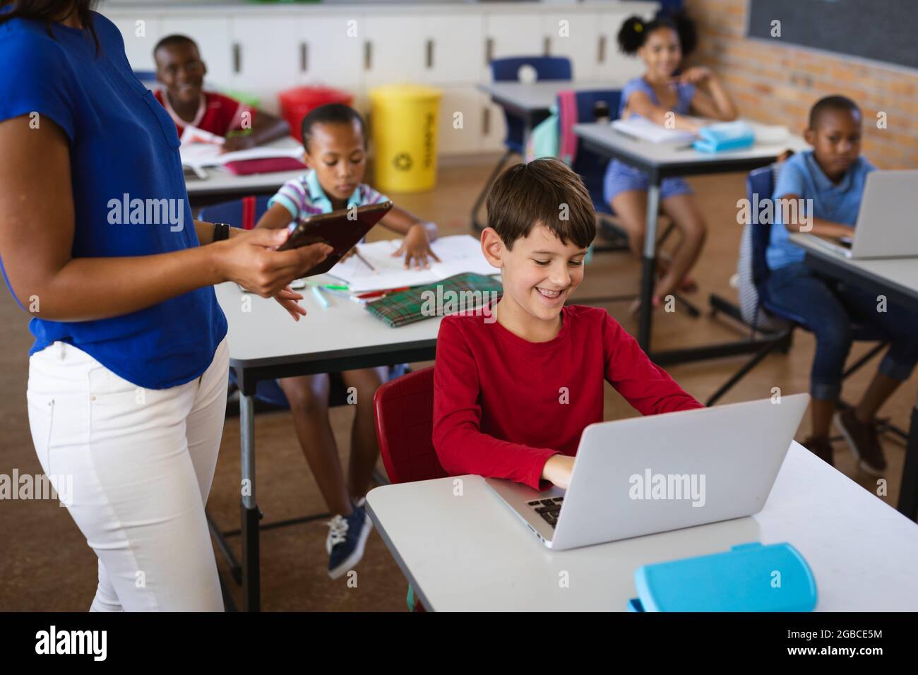 Mid section of female teacher teaching caucasian boy to use digital ...
