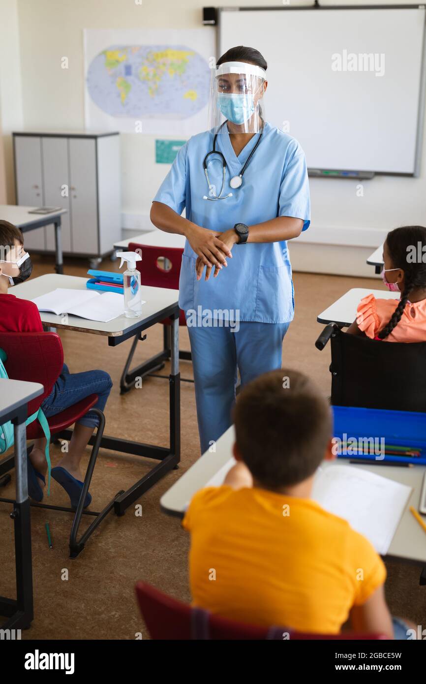 Female health worker showing students to use hands sanitizer in class ...