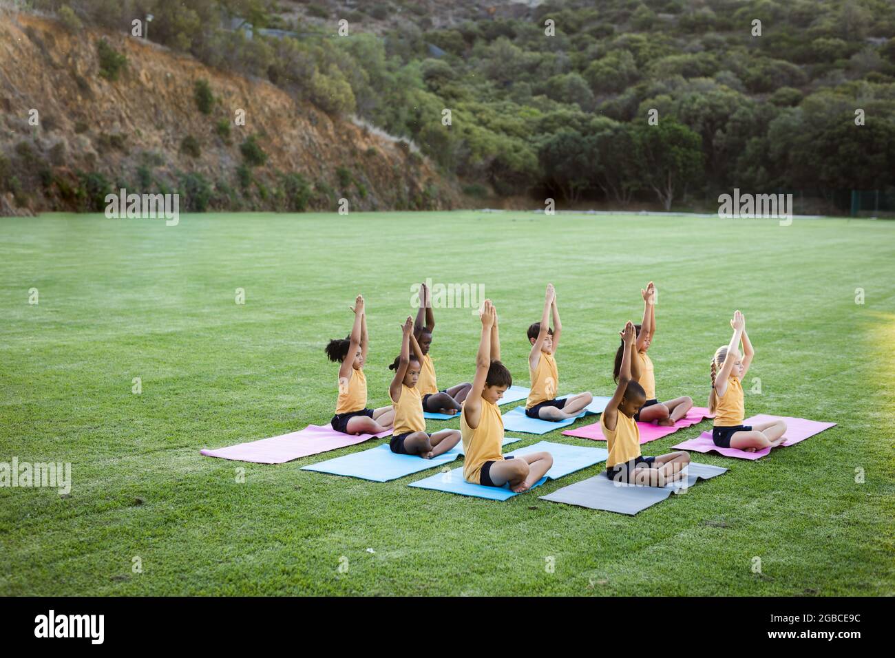 Group of students practicing yoga and meditating sitting on yoga mat in ...