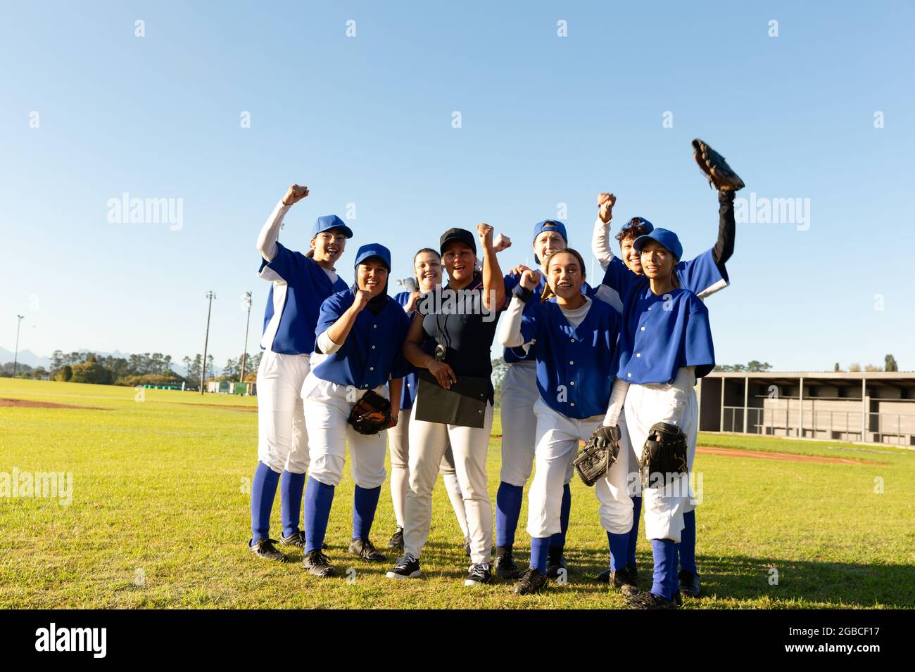 Portrait of diverse group of female baseball players and coach standing ...