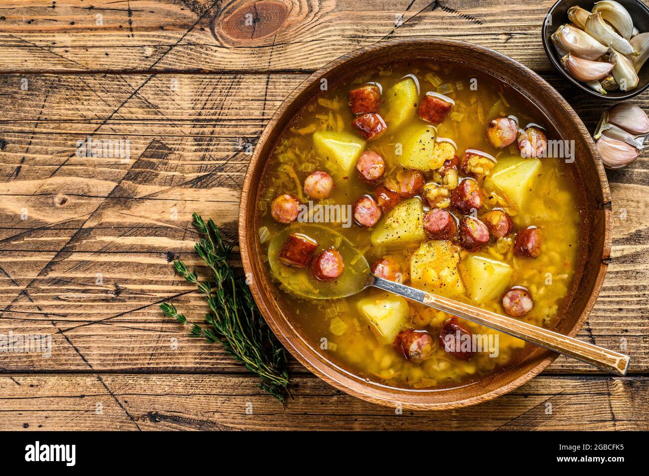 Broth Split pea soup with smoked sausages in a wooden plate. wooden ...