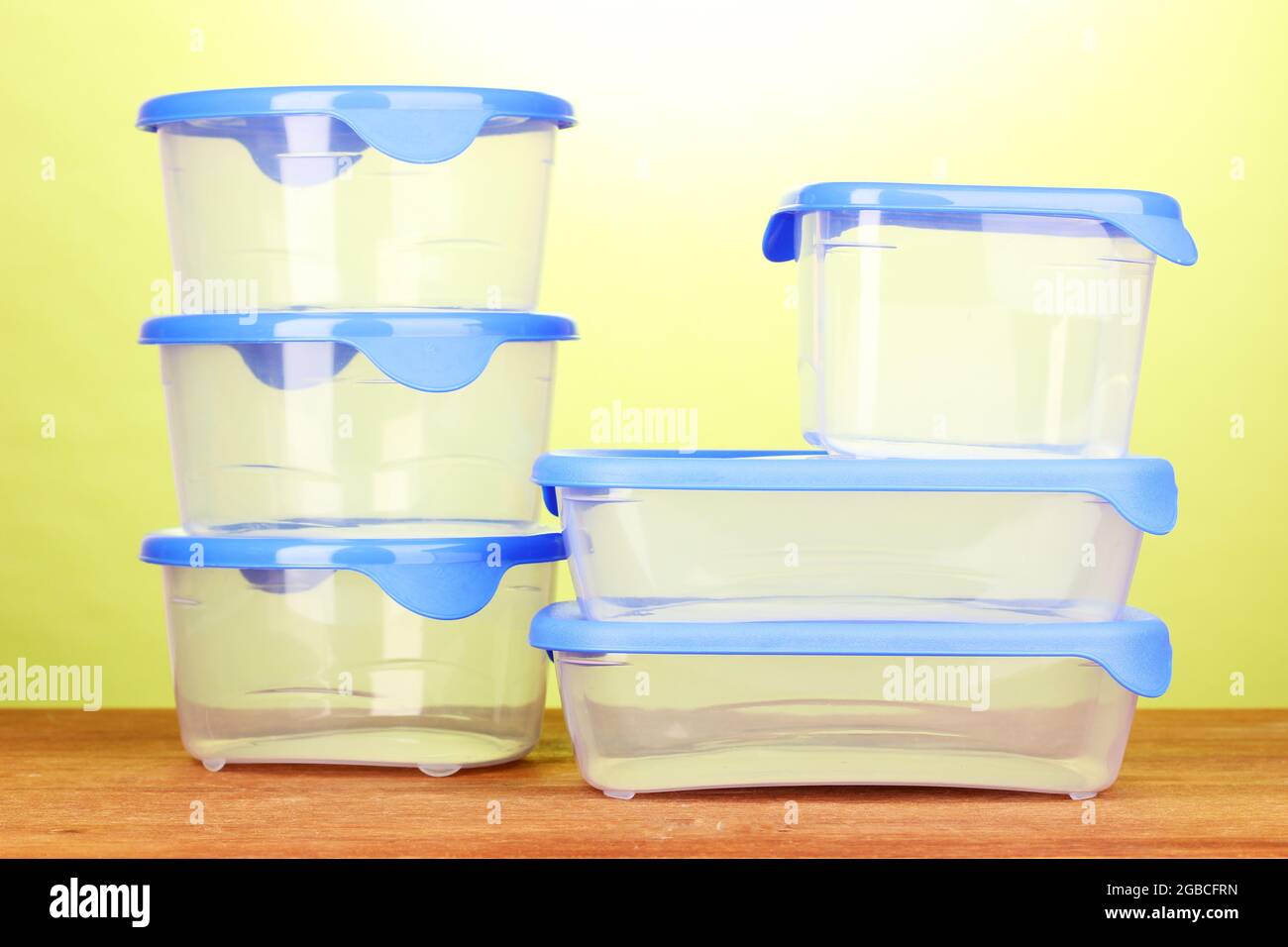 Plastic containers for food on wooden table on green background Stock ...