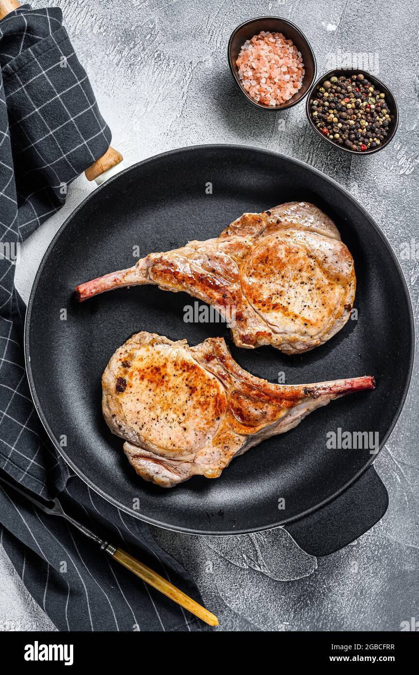 Fried tomahawk pork chop meat steak in a pan. White background. Top ...