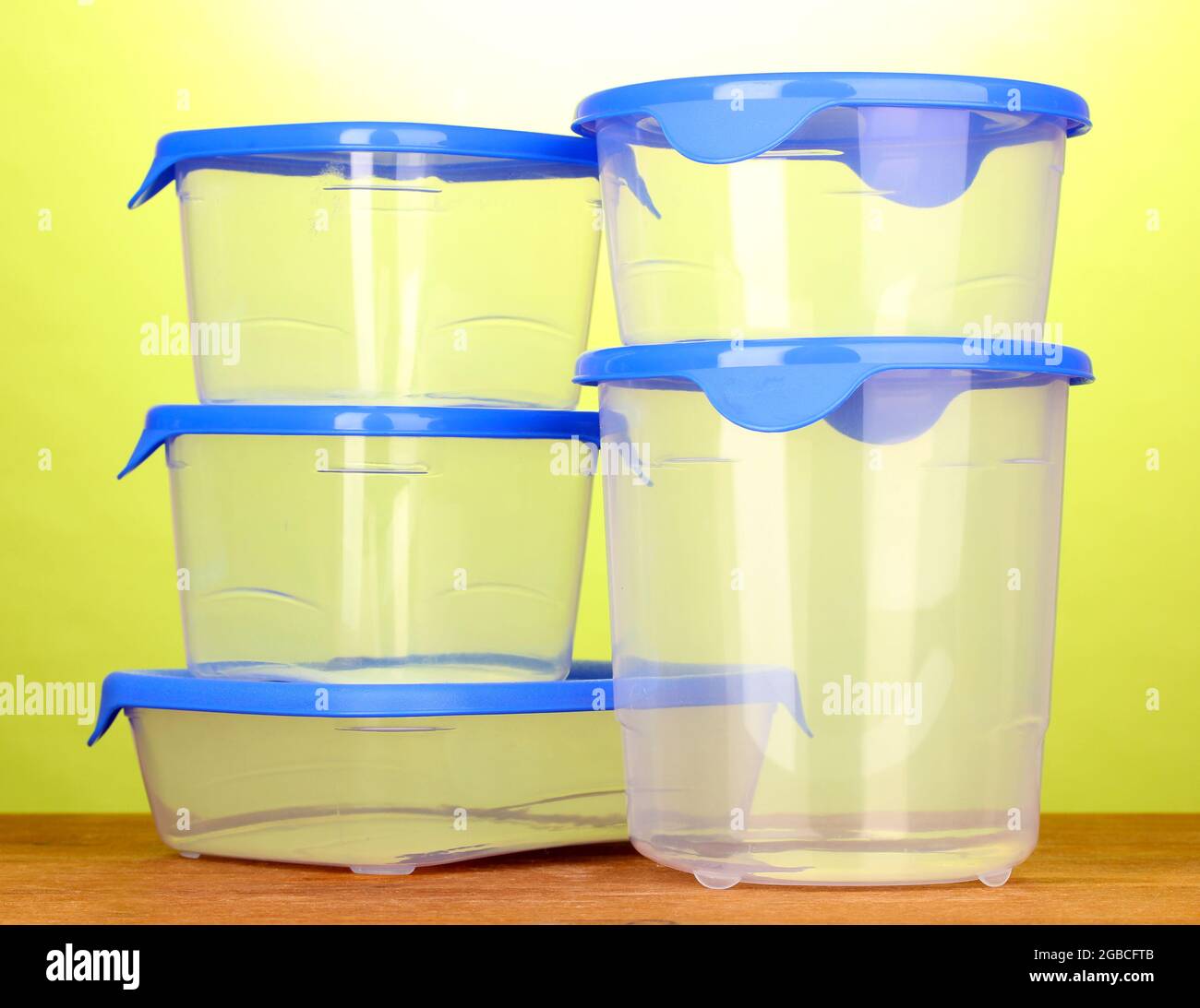 Plastic containers for food on wooden table on green background Stock ...