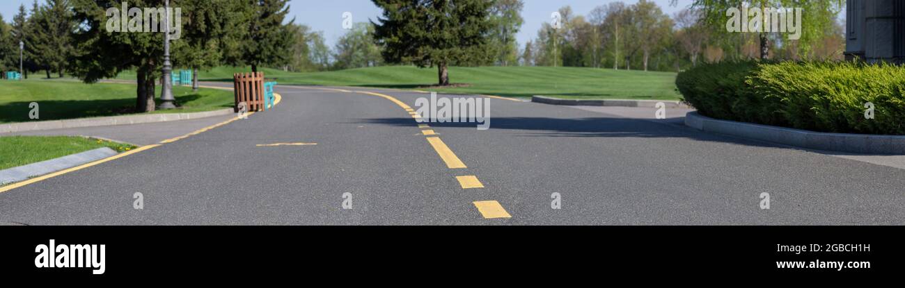 Asphalt path through the park. Beautiful nature, green grass on the ...