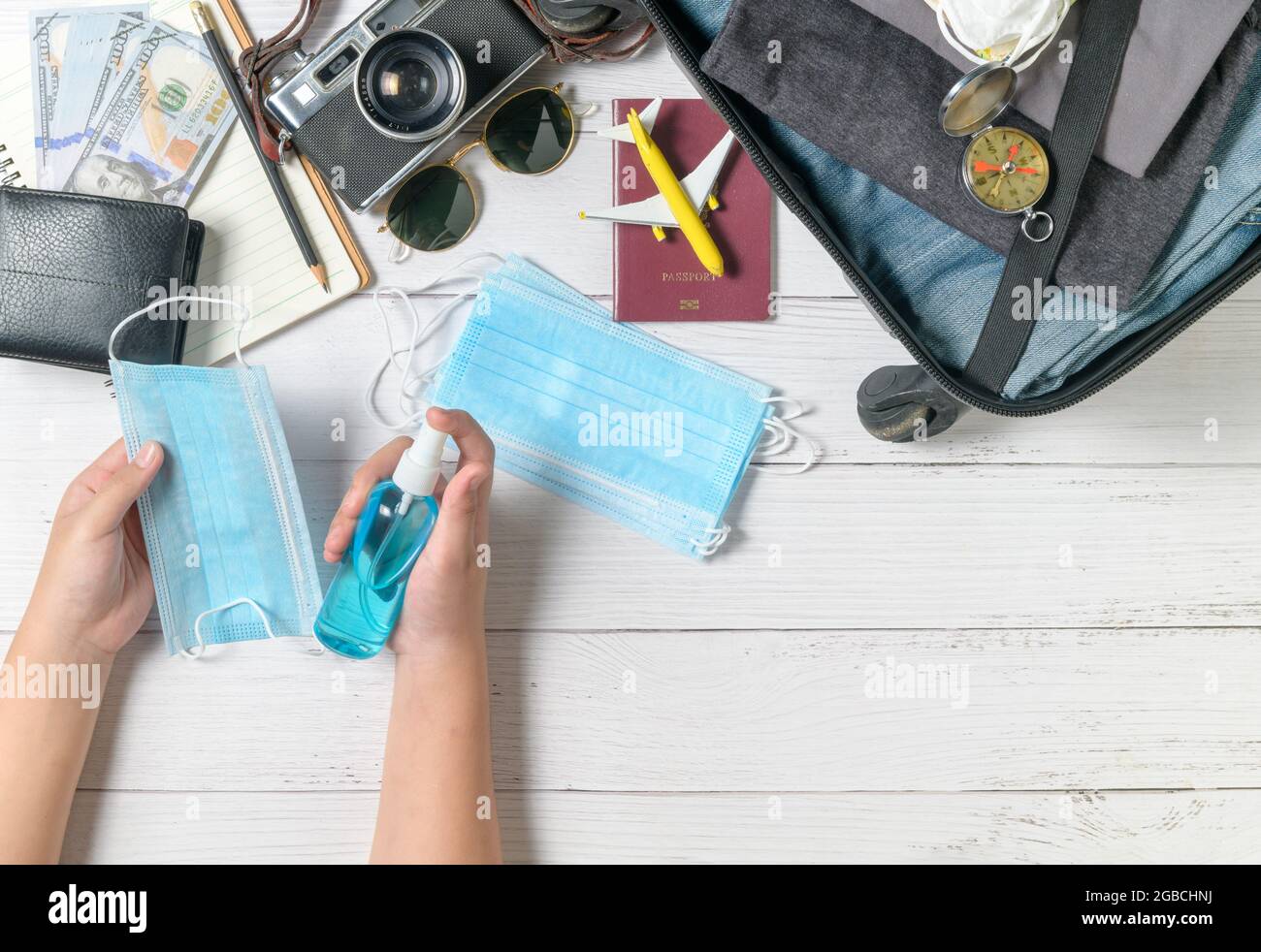 Kid holding mask and alcohol bottle during prepare suitcase, vintage ...