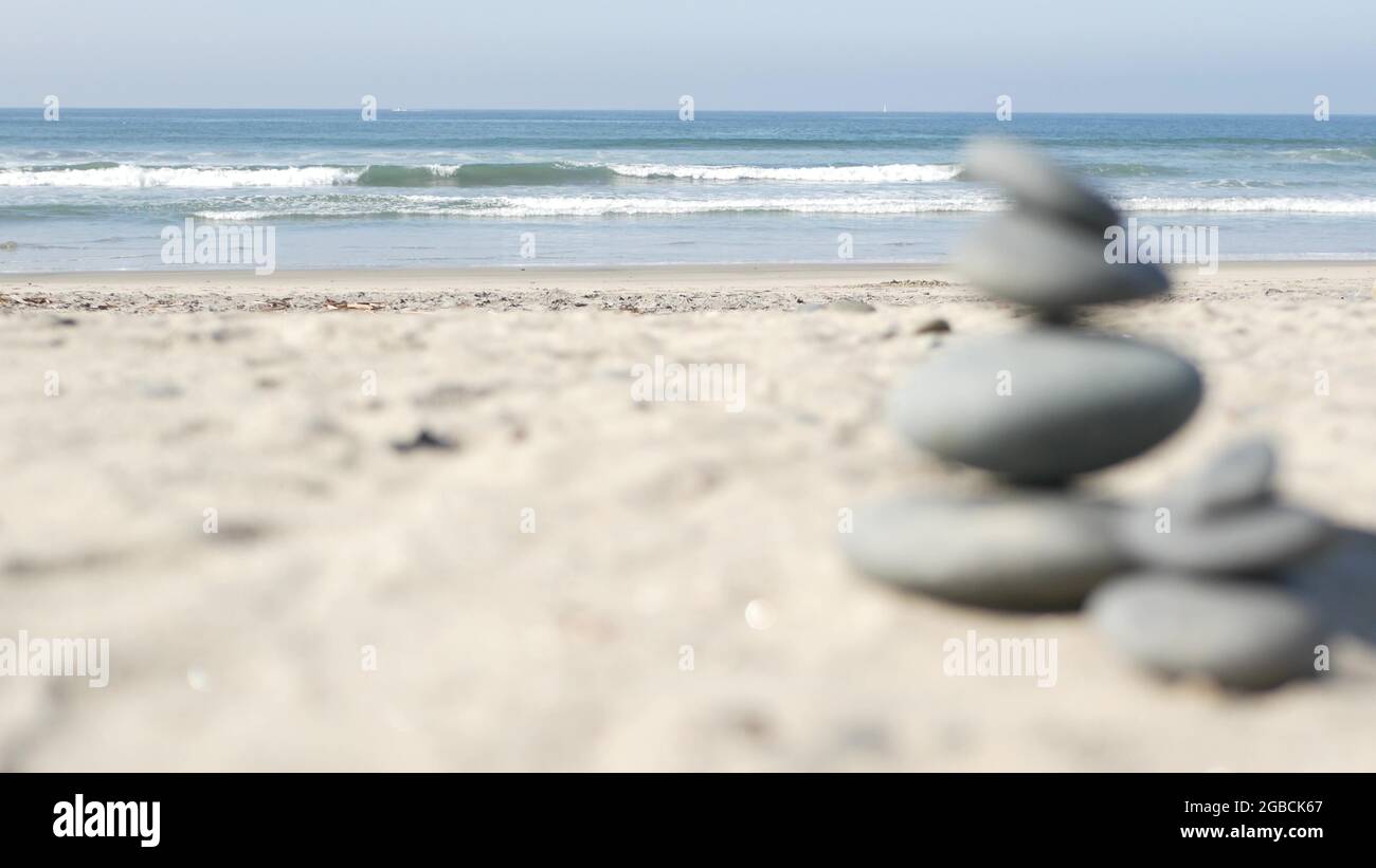 Rock balancing on ocean beach, stones stacking by sea water waves ...