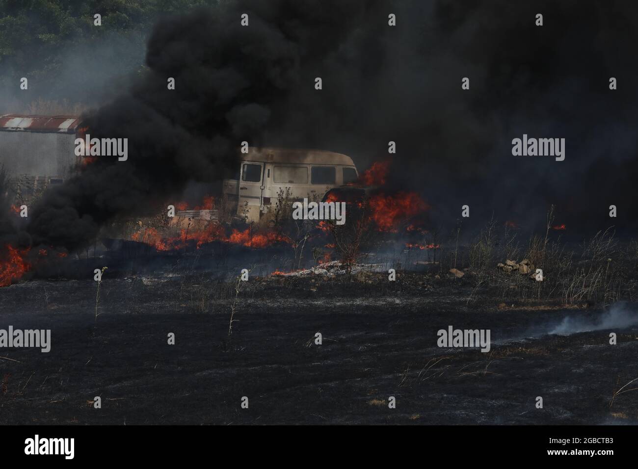 Burning car in a field covered by fire Stock Photo - Alamy