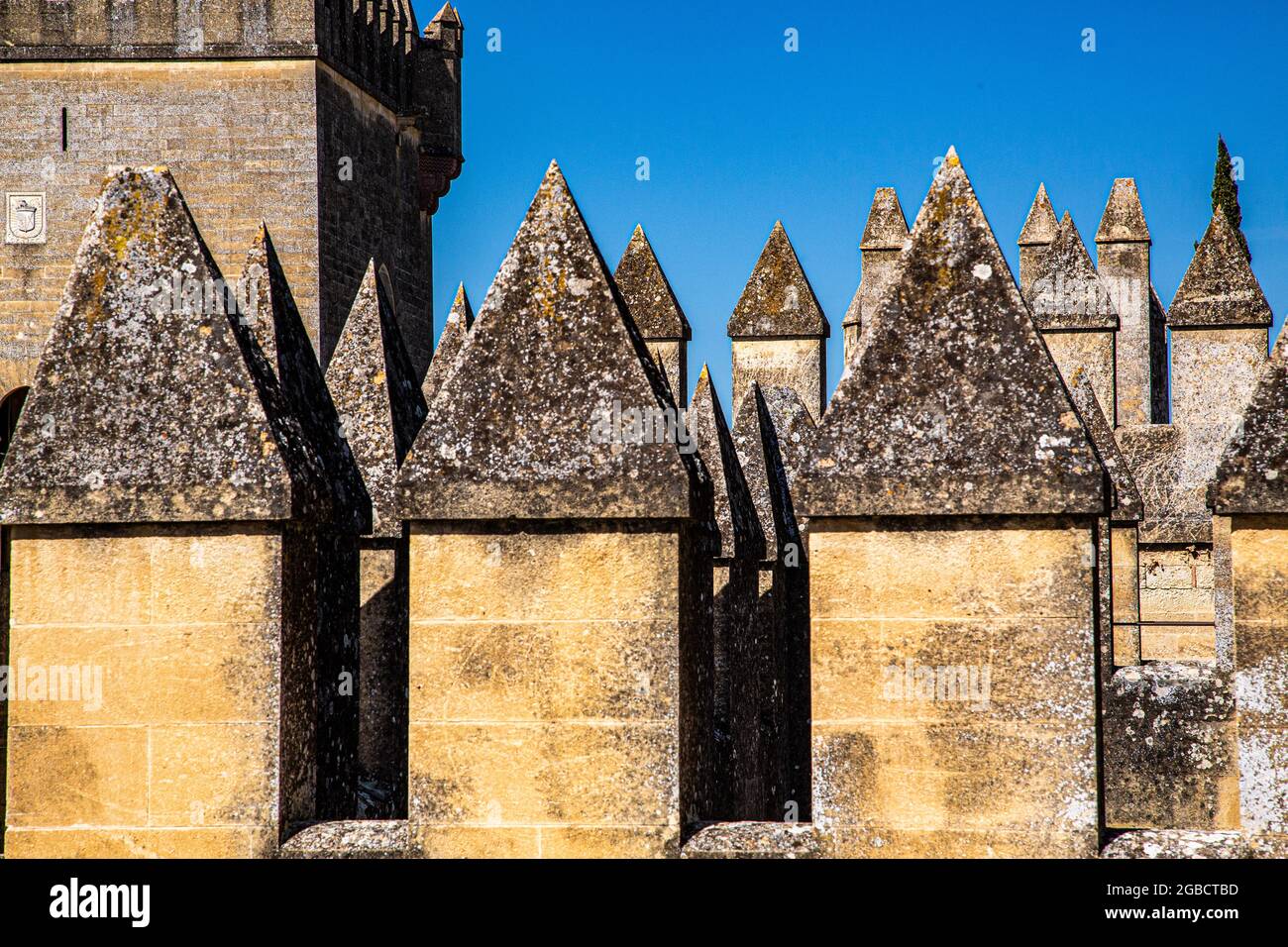 Stone walls and large square towers with defensive walkways at the top ...