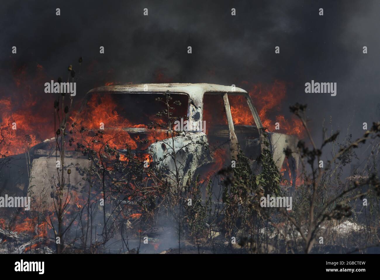 Burning car in a field covered by fire Stock Photo - Alamy