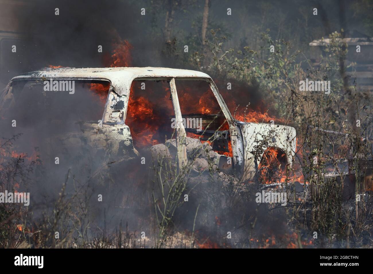 Burning car in a field covered by fire Stock Photo - Alamy