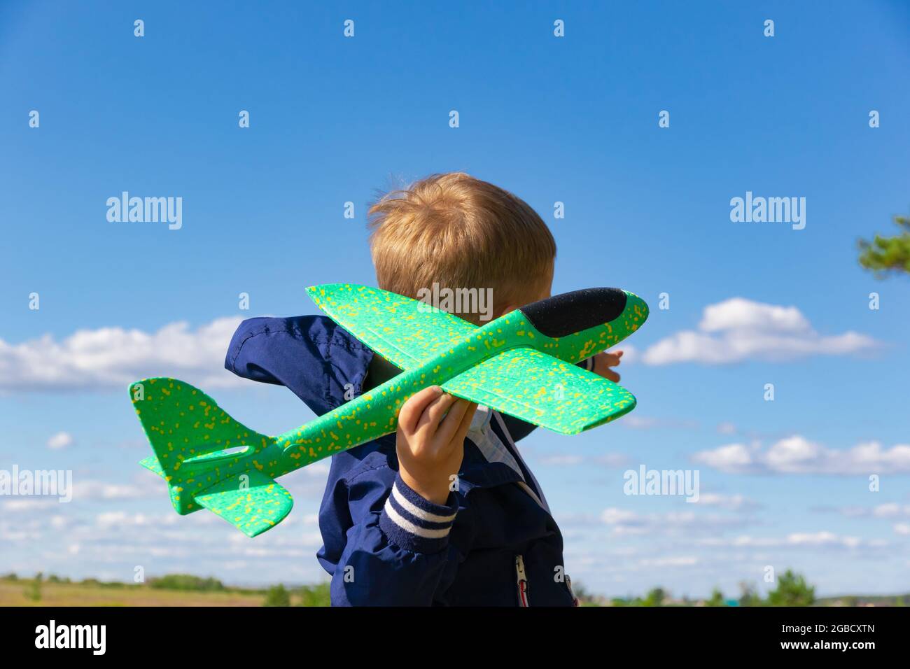 A six-year-old preschooler boy in a blue jacket launches a toy plane in ...