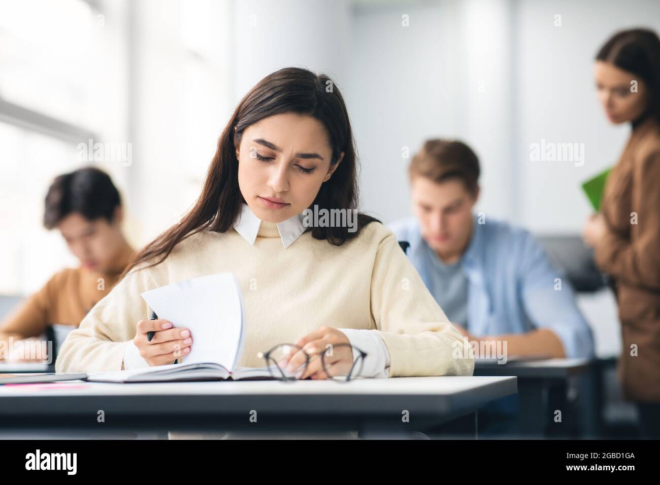 Female student sitting at desk in classroom writing exam Stock Photo ...