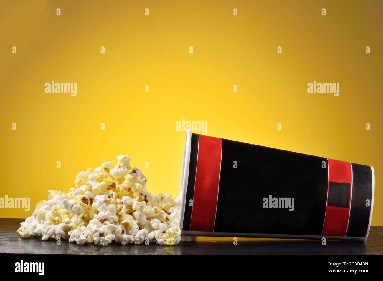 Popcorn bucket fall on table against yellow background Stock Photo - Alamy